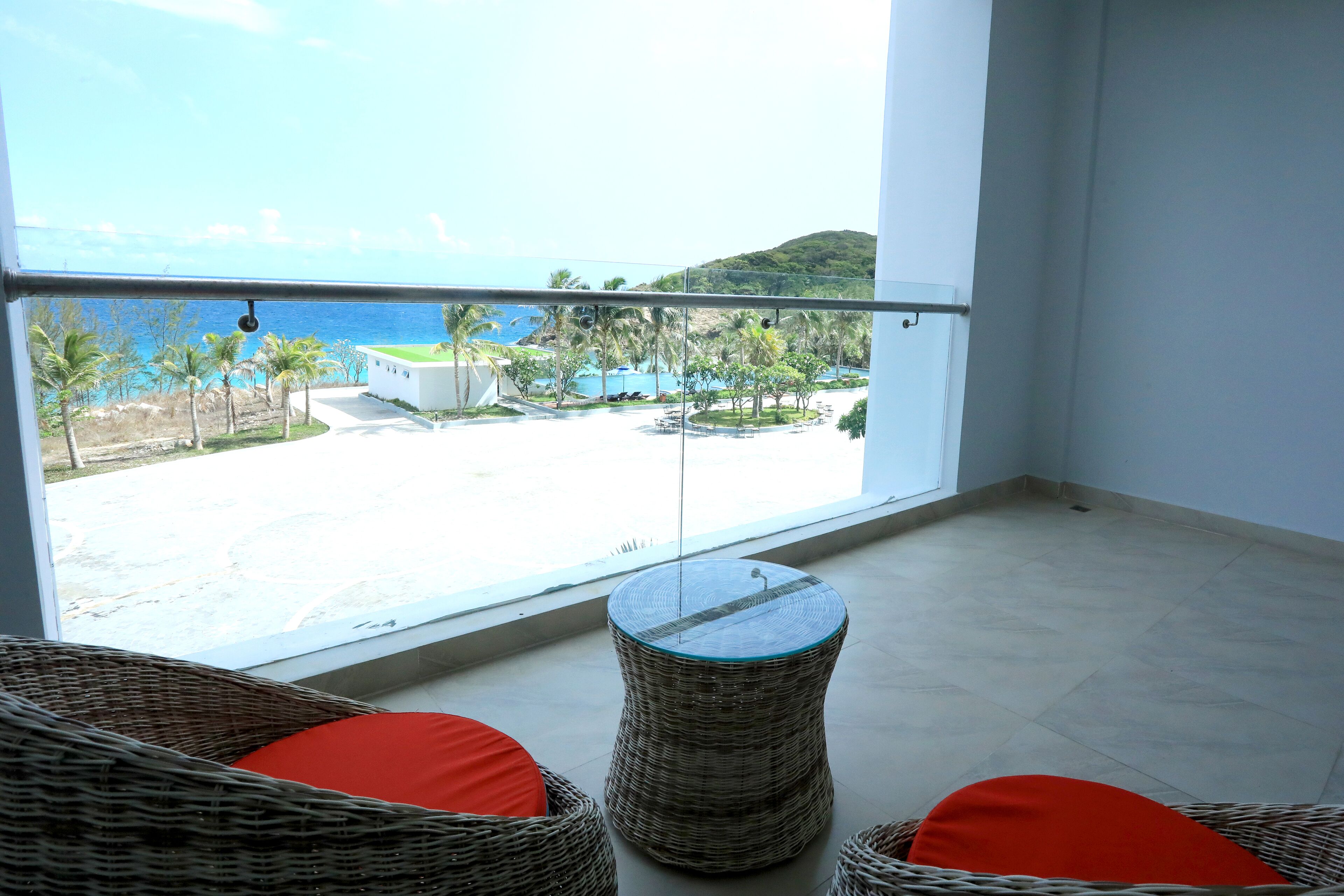 Varanda com mobiliário de vime e vista para um resort à beira-mar.