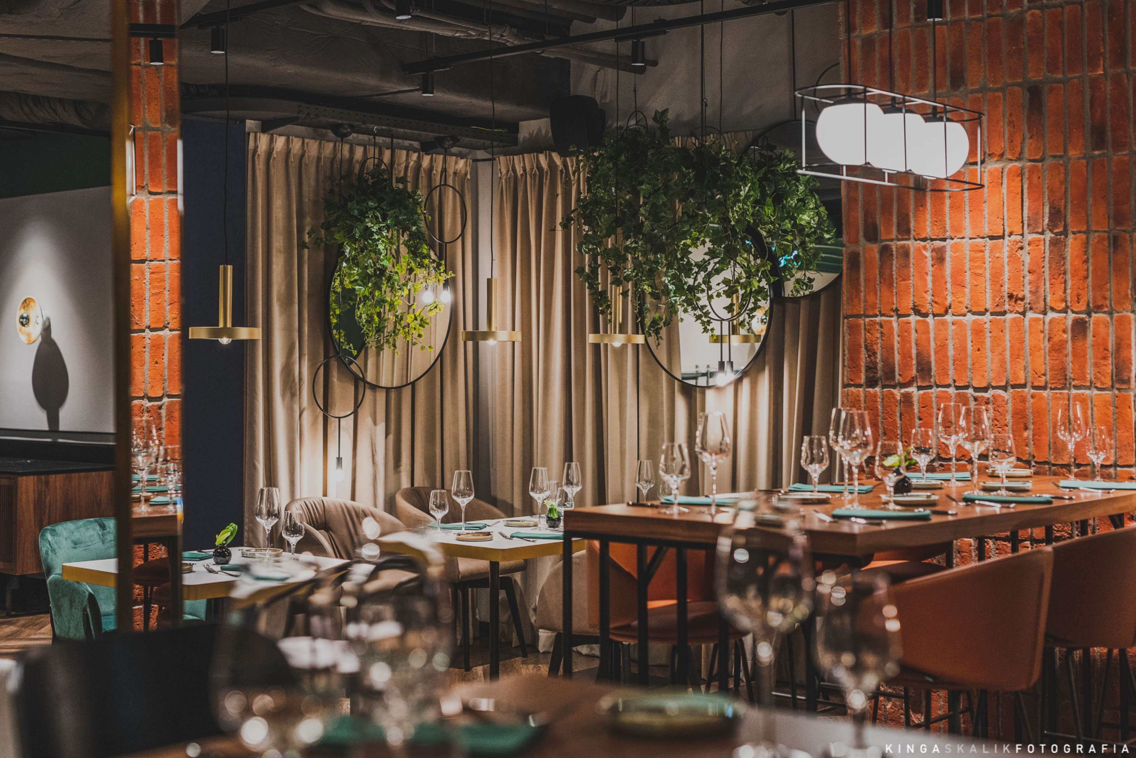 Um restaurante com parede de tijolos, plantas penduradas e uma mesa de jantar bem posta.