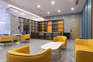 Um lobby moderno com assentos amarelos, uma vitrine de vidro e um balcão de recepção.