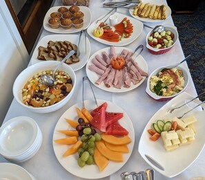 Mesa de buffet com diversos pratos, incluindo frutas, legumes e carnes.