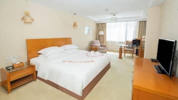 Quarto de hotel com cama, escrivaninha, televisão e cadeira.