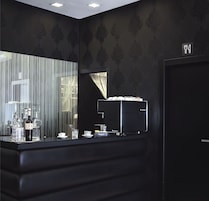 Uma área de recepção de hotel moderna com balcão preto, uma máquina de café e um espelho.
