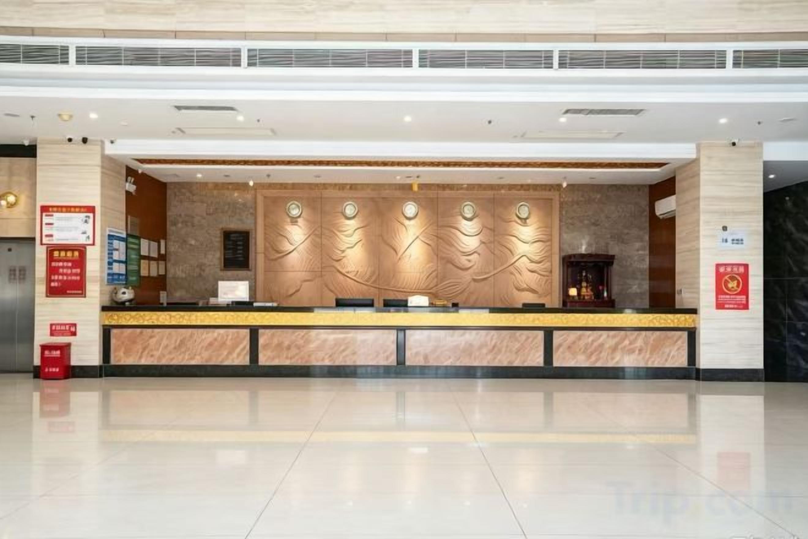 Recepção de hotel com balcão de mármore, painel informativo fixado na parede e sinal de segurança contra incêndio.