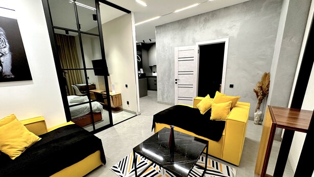 Quarto de hotel moderno com sofá, mesa de centro e área de jantar.
