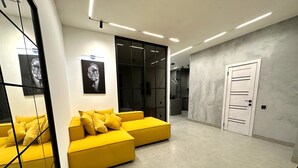 Uma sala de estar moderna com um sofá seccional amarelo, uma janela grande e uma porta que dá para outro cômodo.