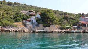 Um imóvel costeiro com uma parede de pedra, uma piscina pequena e vista para o mar.