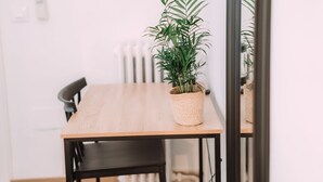 Uma mesa de madeira com um cachepot trançado, uma cadeira preta e um radiador ao fundo.