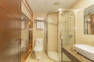 Casa de banho moderna com chuveiro em cabine de vidro, sanita branca e bancada de mármore com lavatório.
