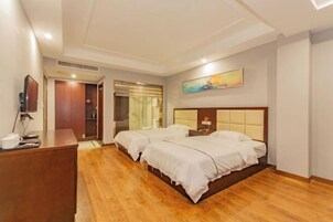 Quarto de hotel com duas camas, uma escrivaninha, um quadro e vista para o exterior.