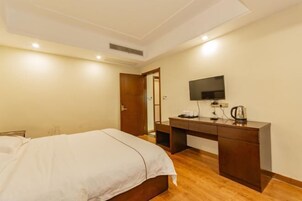 Quarto de hotel com cama, escrivaninha, televisão e cafeteira.
