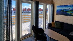 Quarto com uma grande porta de vidro deslizante que dá para uma área externa nevada, teto de madeira e um quadro na parede.
