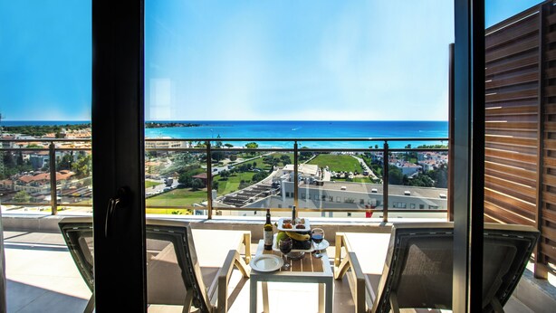 Varanda com mesa posta para dois, com vista para a costa.