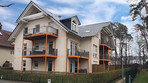 Um edifício residencial de vários andares com varandas, entrada fechada e um gramado bem cuidado.