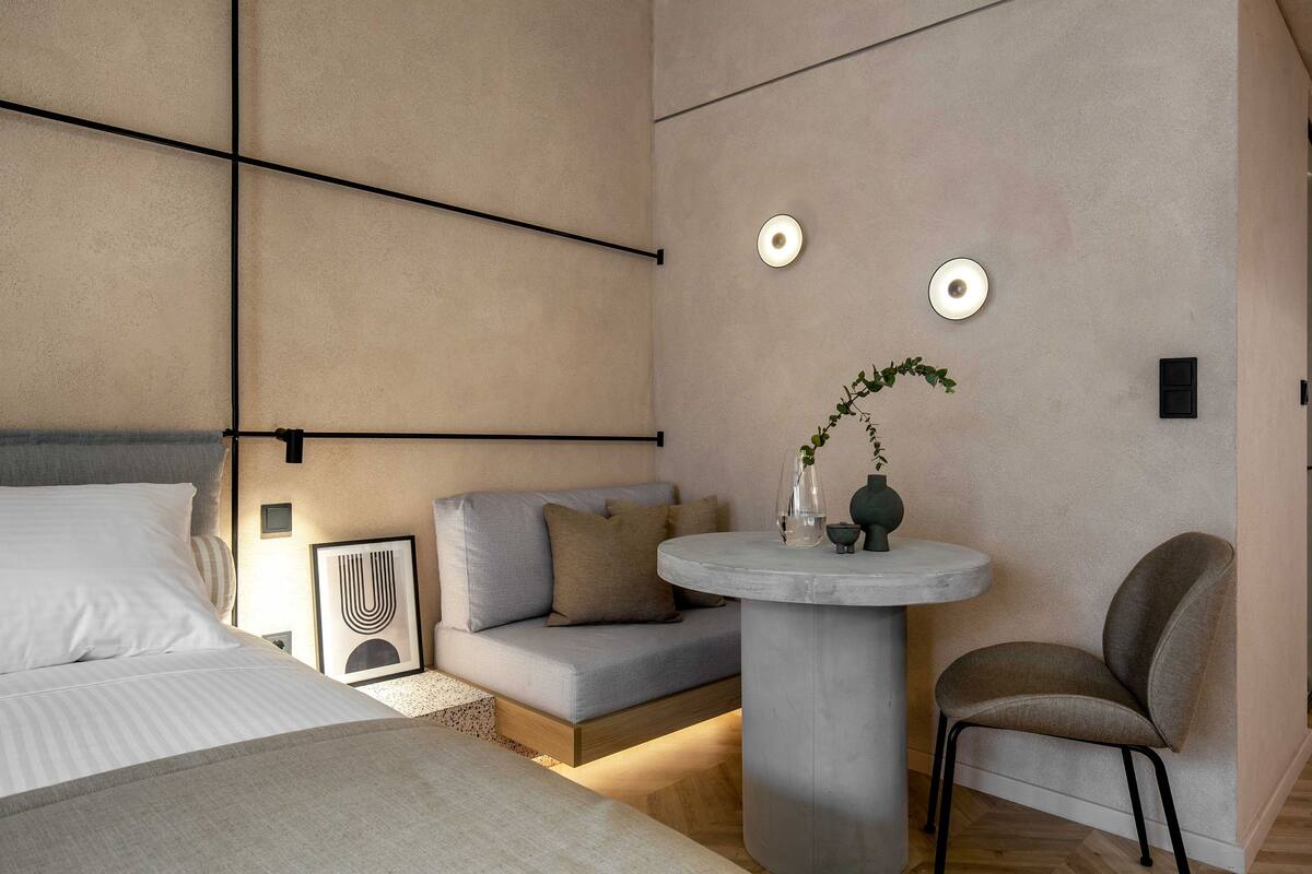 Um quarto moderno com uma cama, um sofá, uma mesa redonda e uma cadeira.