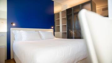 Quarto de hotel moderno com uma cama grande, um guarda-roupa e uma mesa de cabeceira.