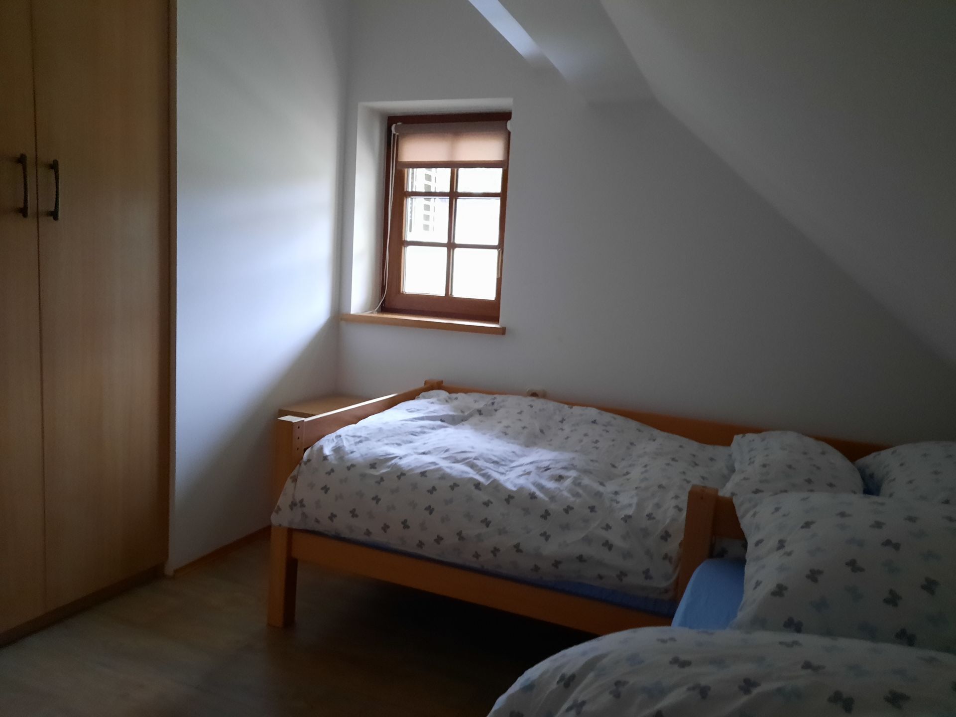Quarto com uma cama de solteiro, uma janela e um guarda-roupa.