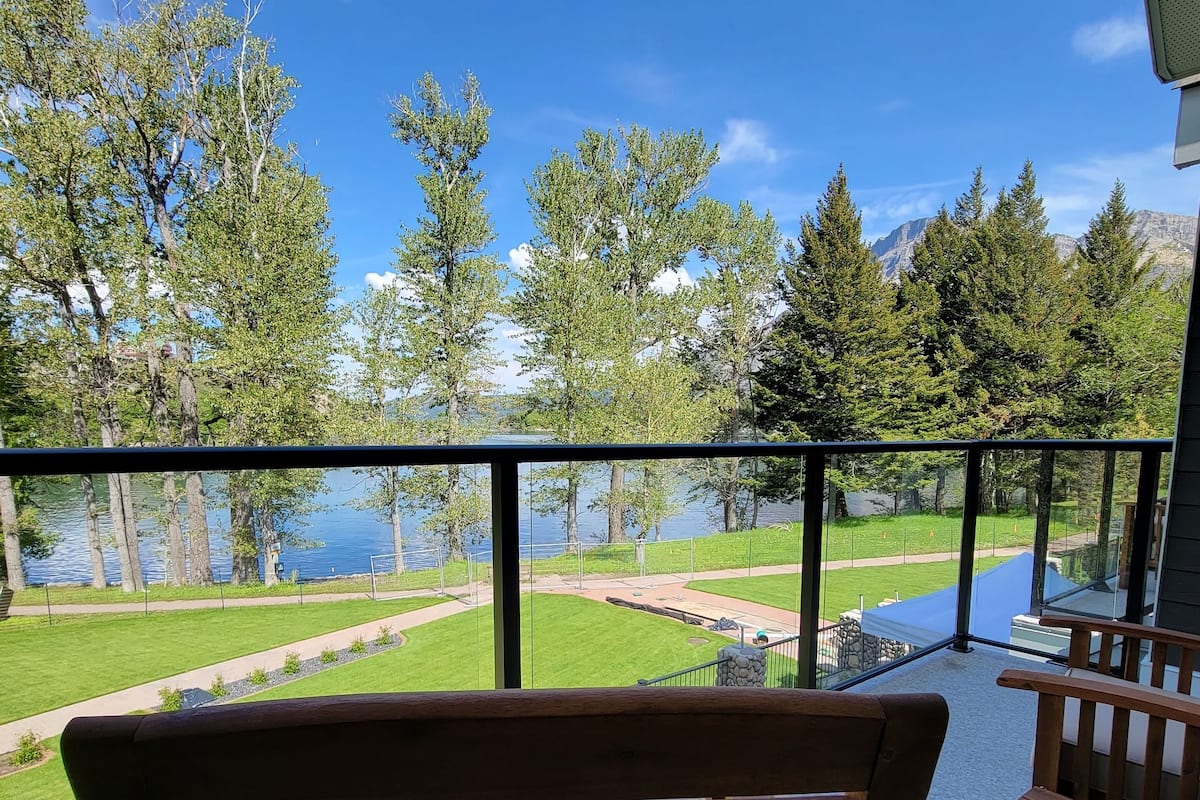 Um deck de madeira com vista para um lago e árvores.