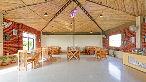 Um restaurante espaçoso com teto de madeira alto, paredes de tijolo e chão de azulejos polidos.