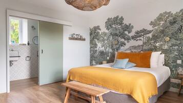Quarto com cama, um banco, um mural na parede e uma janela.