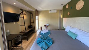 Quarto de hotel com cama, televisão, escrivaninha e uma escada.