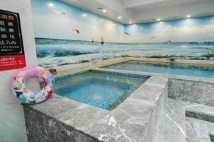 Piscina com mural do oceano e pássaros, boia inflável infantil e placa com texto.