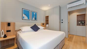 Quarto moderno com uma cama grande, mesa de cabeceira, guarda-roupa e duas fotos emolduradas na parede.