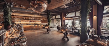 Um espaço amplo de bar com um balcão comprido, diversas opções de assento e uma grande bola de discoteca.