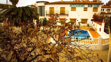 Um edifício com uma placa que diz "RESTAURANT BON LLOC" e uma piscina.