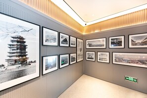 Uma galeria com fotografias emolduradas numa parede, uma grande fotografia de um pagode e uma placa de indicação.