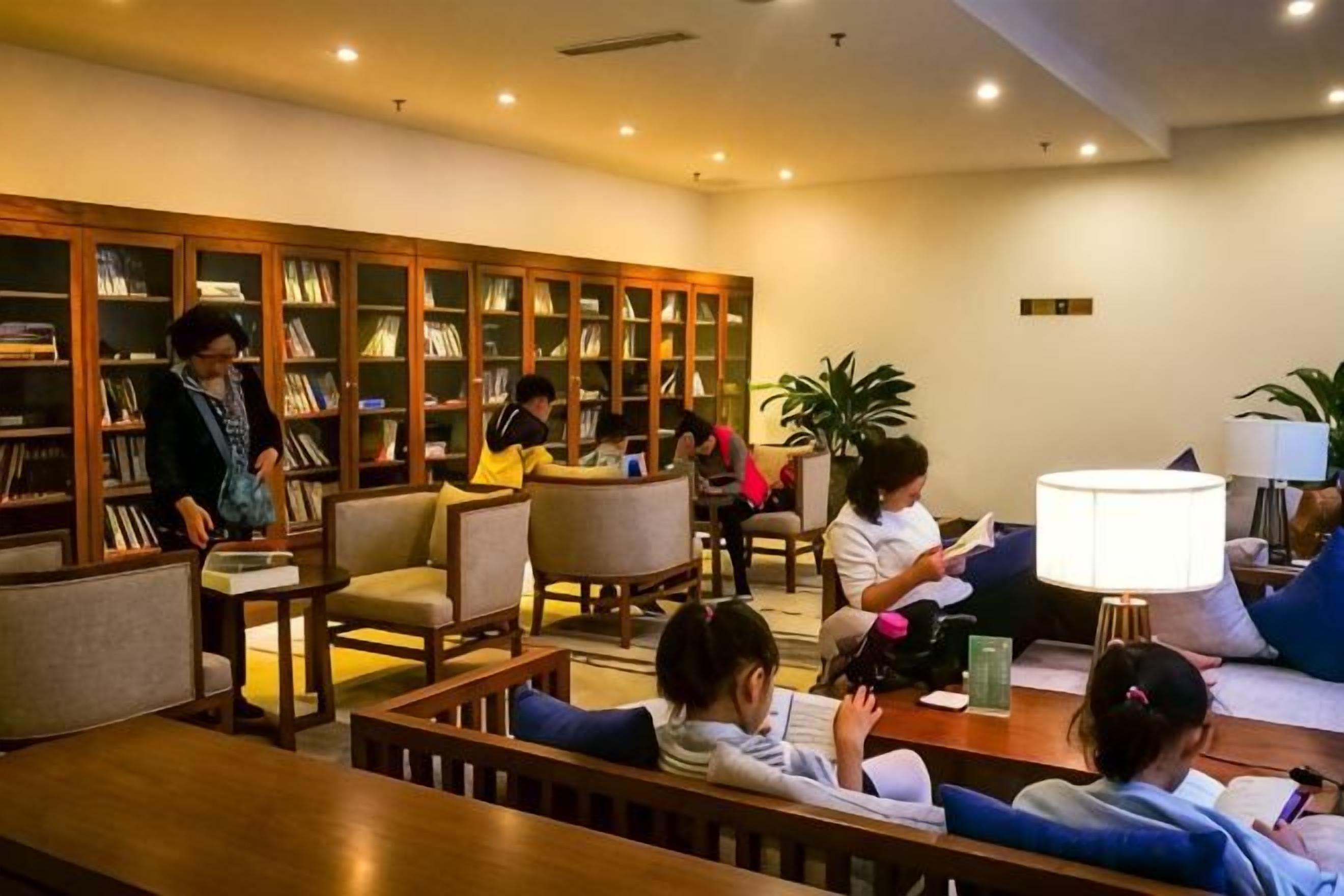Uma biblioteca com estantes, áreas de estar e uma mesa com abajur.