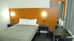 Quarto de hotel com cama, mesas de cabeceira, escrivaninha e uma cadeira.