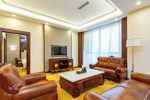 Uma sala de estar moderna com sofás de couro, uma TV de tela plana e uma mesa de centro.