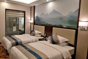 Quarto de hotel com duas camas, uma porta de vidro e um mural grande na parede com paisagem montanhosa.