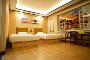 Quarto de hotel com duas camas, uma escrivaninha e janela com vista para a cidade.