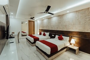Quarto de hotel moderno com duas camas, uma televisão, uma escrivaninha e um ventilador de teto.