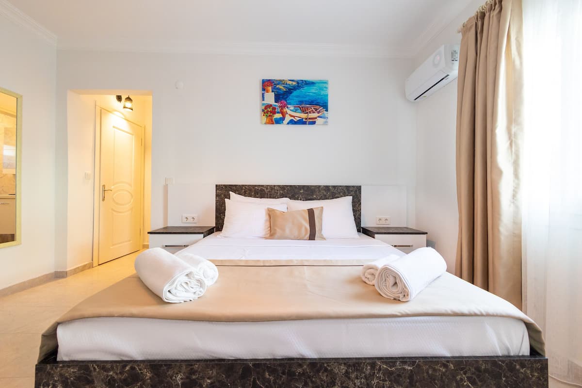 Quarto de hotel com cama, quadro, porta e unidade de ar condicionado.