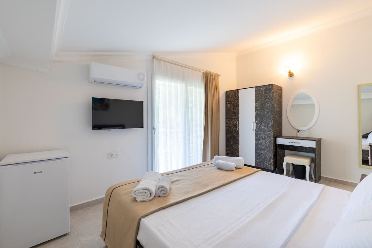 Quarto de hotel com cama, escrivaninha, cadeira, televisão e ar condicionado.