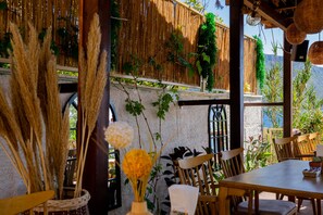 Um restaurante com móveis de madeira, um cesto de vime e plantas penduradas.