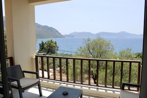 Varanda com vista para um lago e montanhas. Há uma cadeira e uma mesa na varanda.