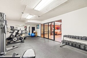 Uma academia com equipamentos de exercícios, um banco de musculação e um relógio digital.