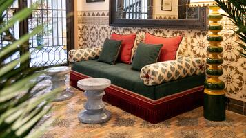 Uma área de estar acolhedora, com um sofá estampado, almofadas decorativas e um chão com padrão.