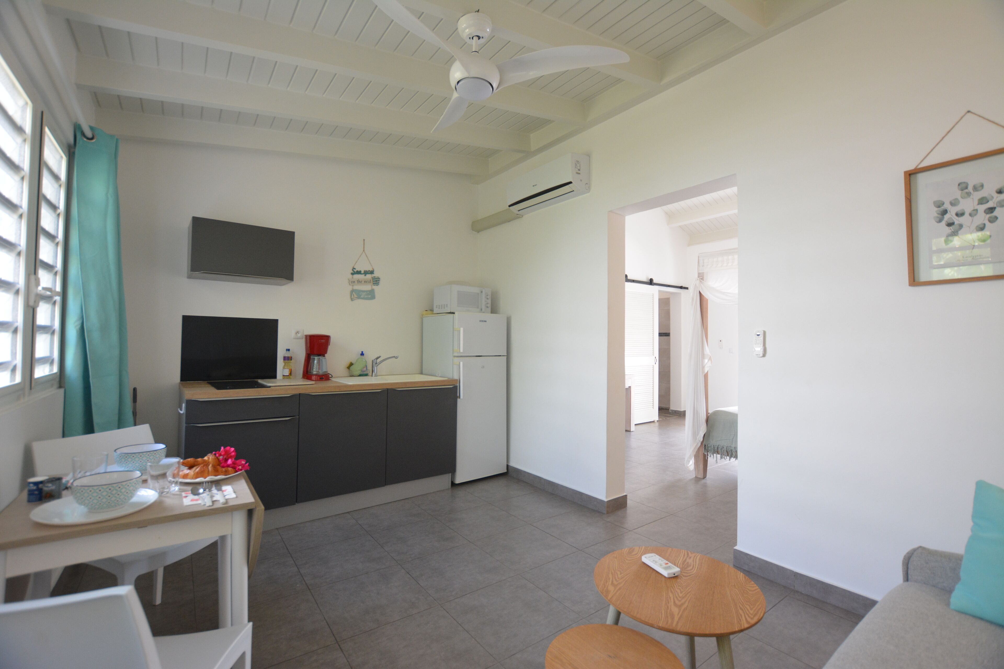 Uma cozinha compacta com área de refeições, um ventilador de teto e vista para a sala de estar.