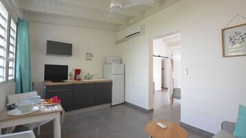 Uma cozinha compacta com área de refeições, um ventilador de teto e vista para a sala de estar.
