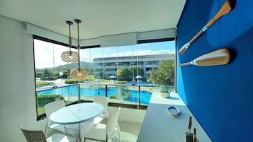 Quarto com vista para uma piscina, uma mesa com cadeiras e uma parede azul com banheiras.
