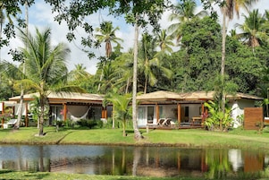Um resort tropical com duas villas, um lago e vegetação exuberante.