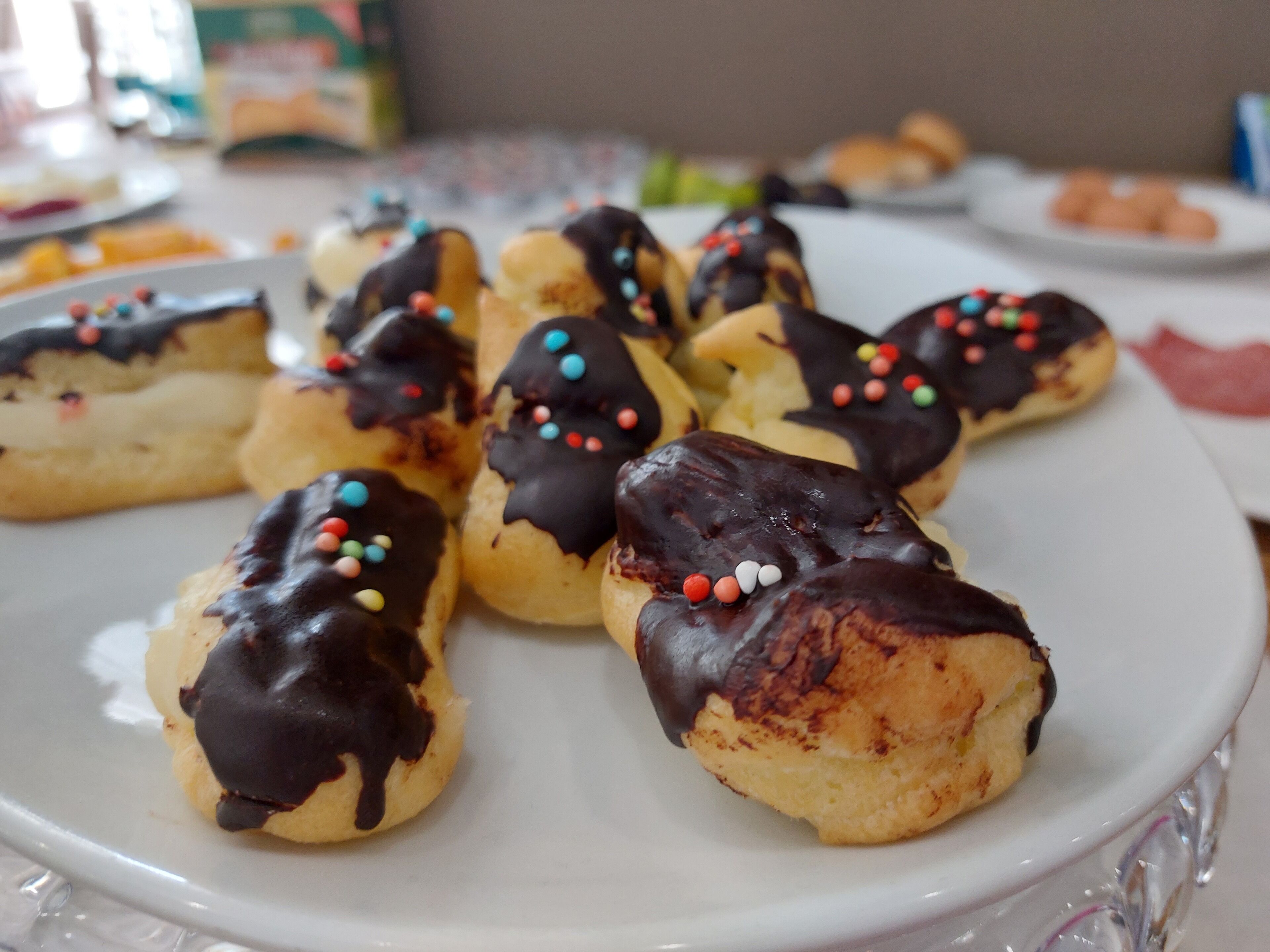 Um prato de doces mergulhados em chocolate com confeitos coloridos.