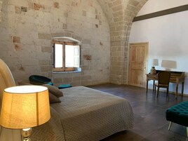 Quarto com cama, escrivaninha, cadeira e janela.