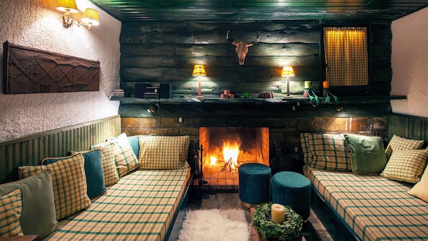 Um quarto acolhedor com um sofá estampado em xadrez, lareira e teto de madeira.
