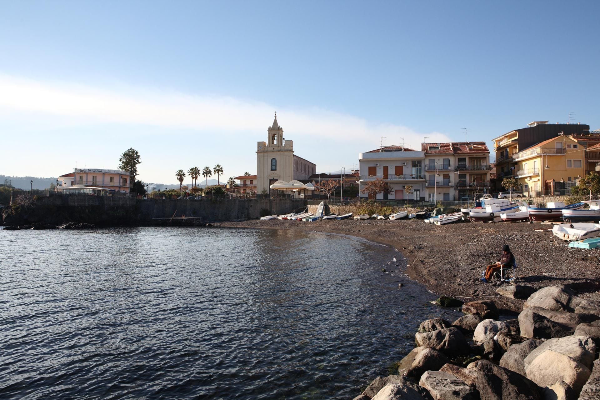Uma vila costeira com uma igreja, edifícios residenciais e barcos na orla.