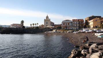 Uma vila costeira com uma igreja, edifícios residenciais e barcos na orla.